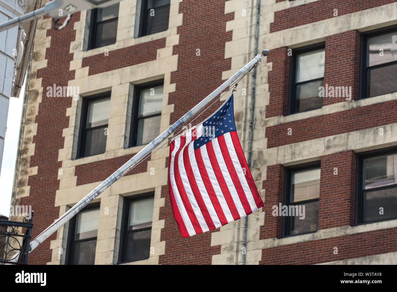Hanging off the side of one building with brick facade in background ...