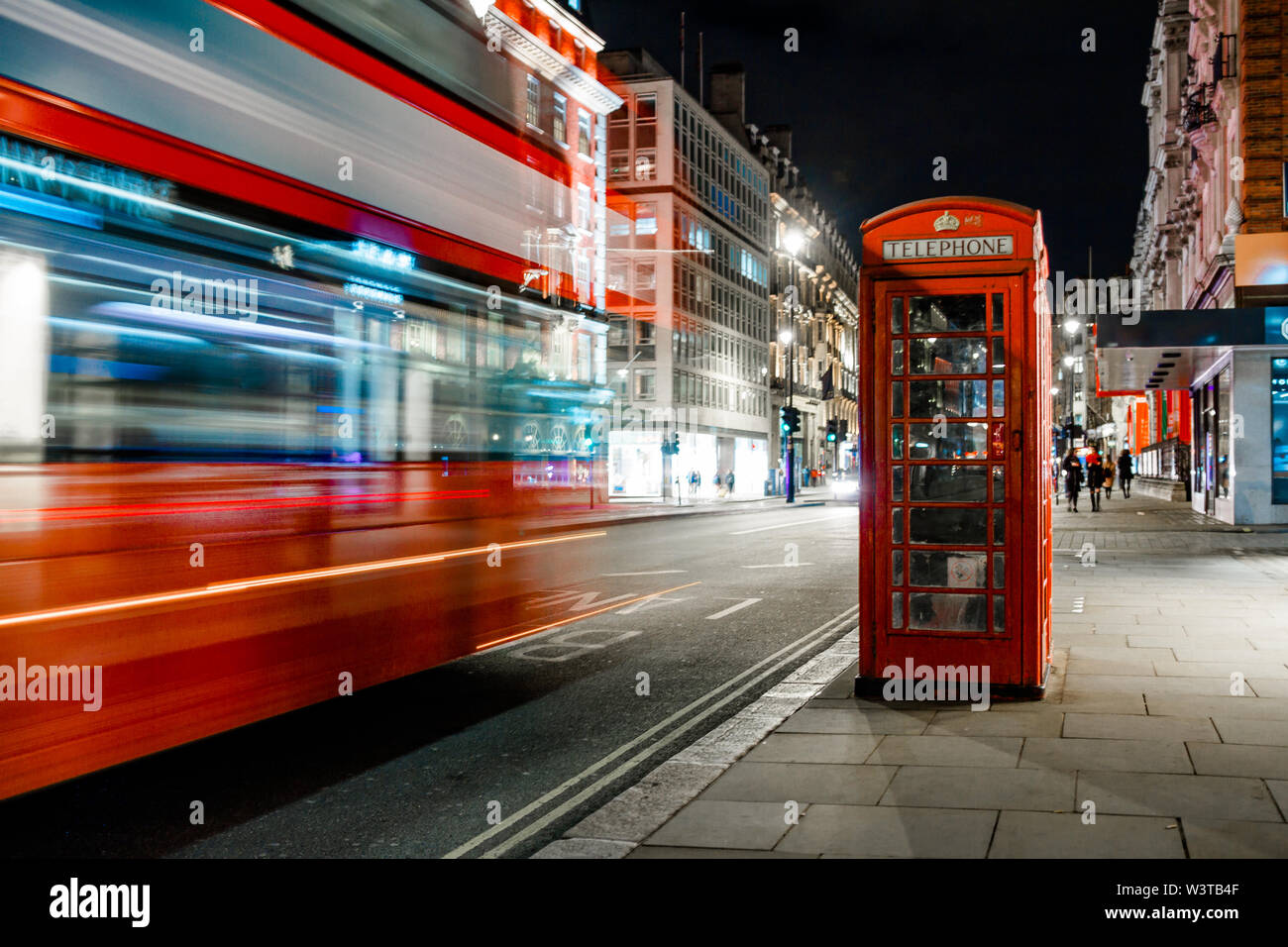 Light trails of a double decker bus next to the iconic telephone booth ...
