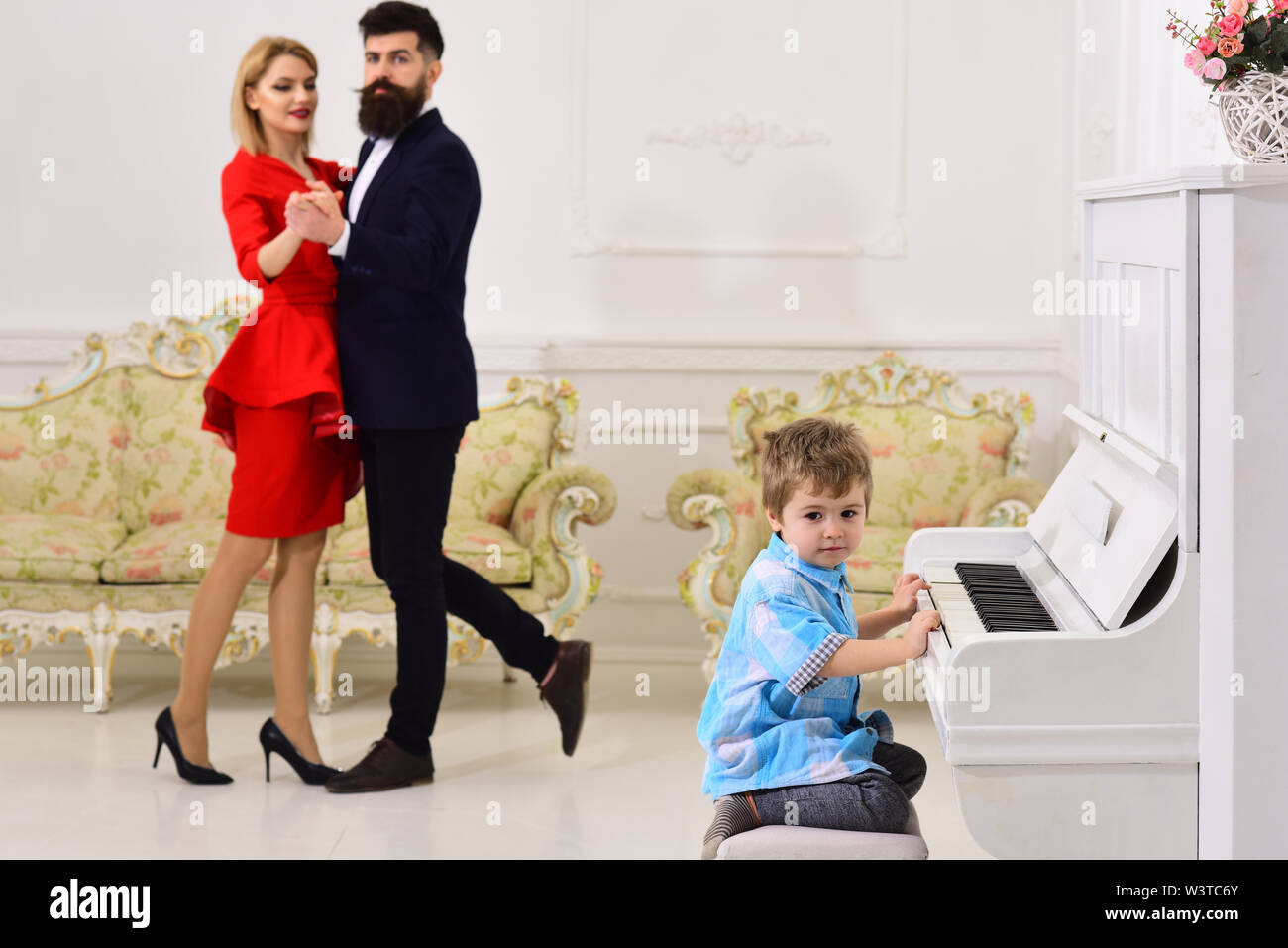 Child sit next to piano, play music, white interior background ...