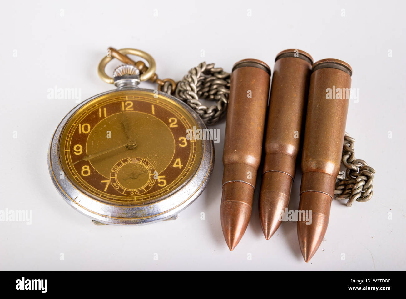 Old clock and ammunition on a white table. Explosive material and time ...