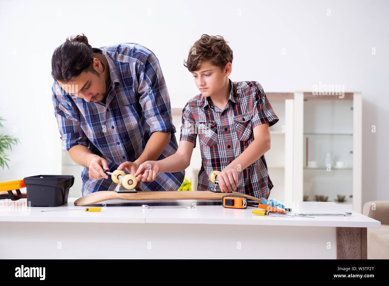The young father repairing skateboard with his son at home Stock Photo ...