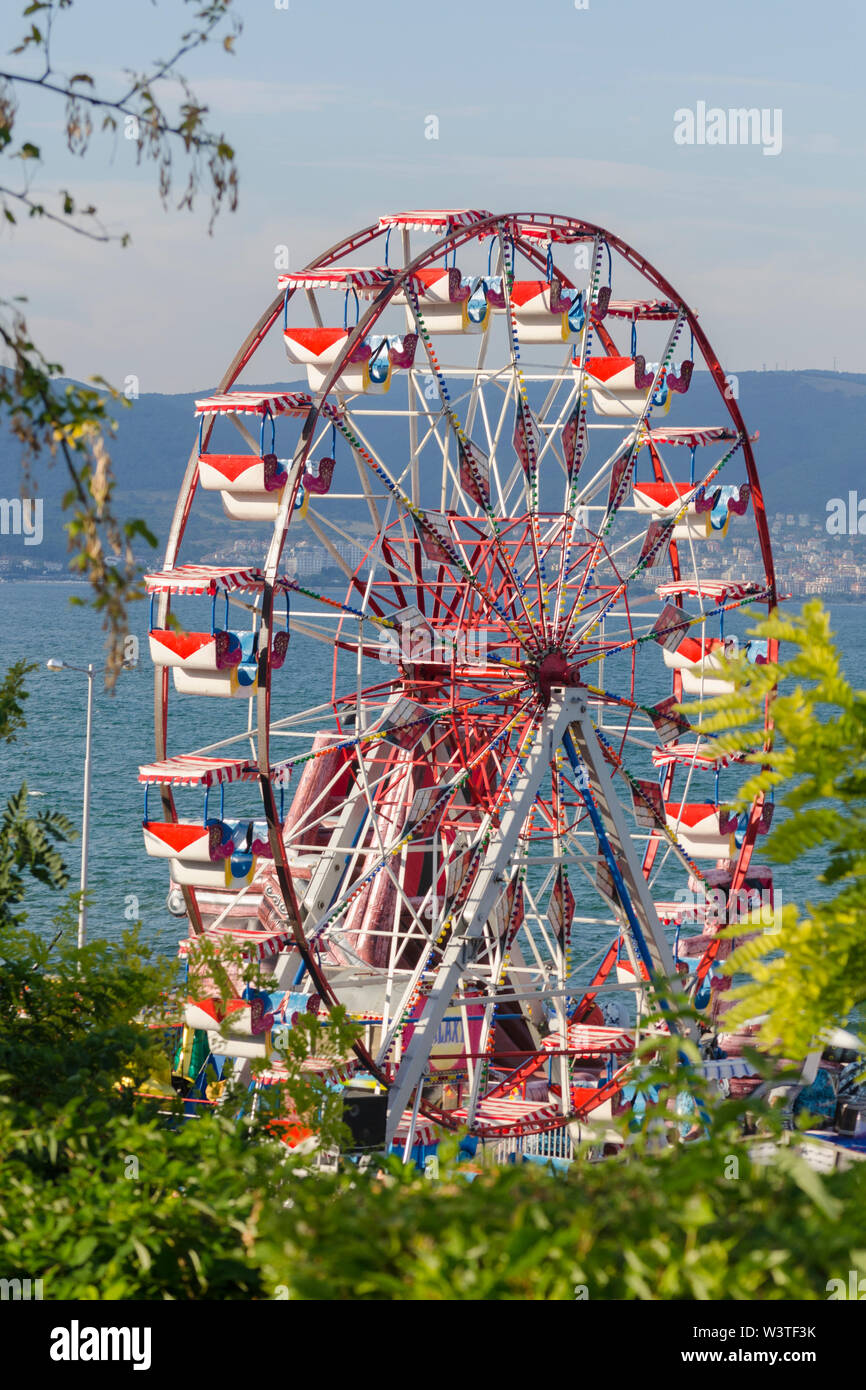 A colourful ferris wheel in the city amusement park at sunny summer day ...