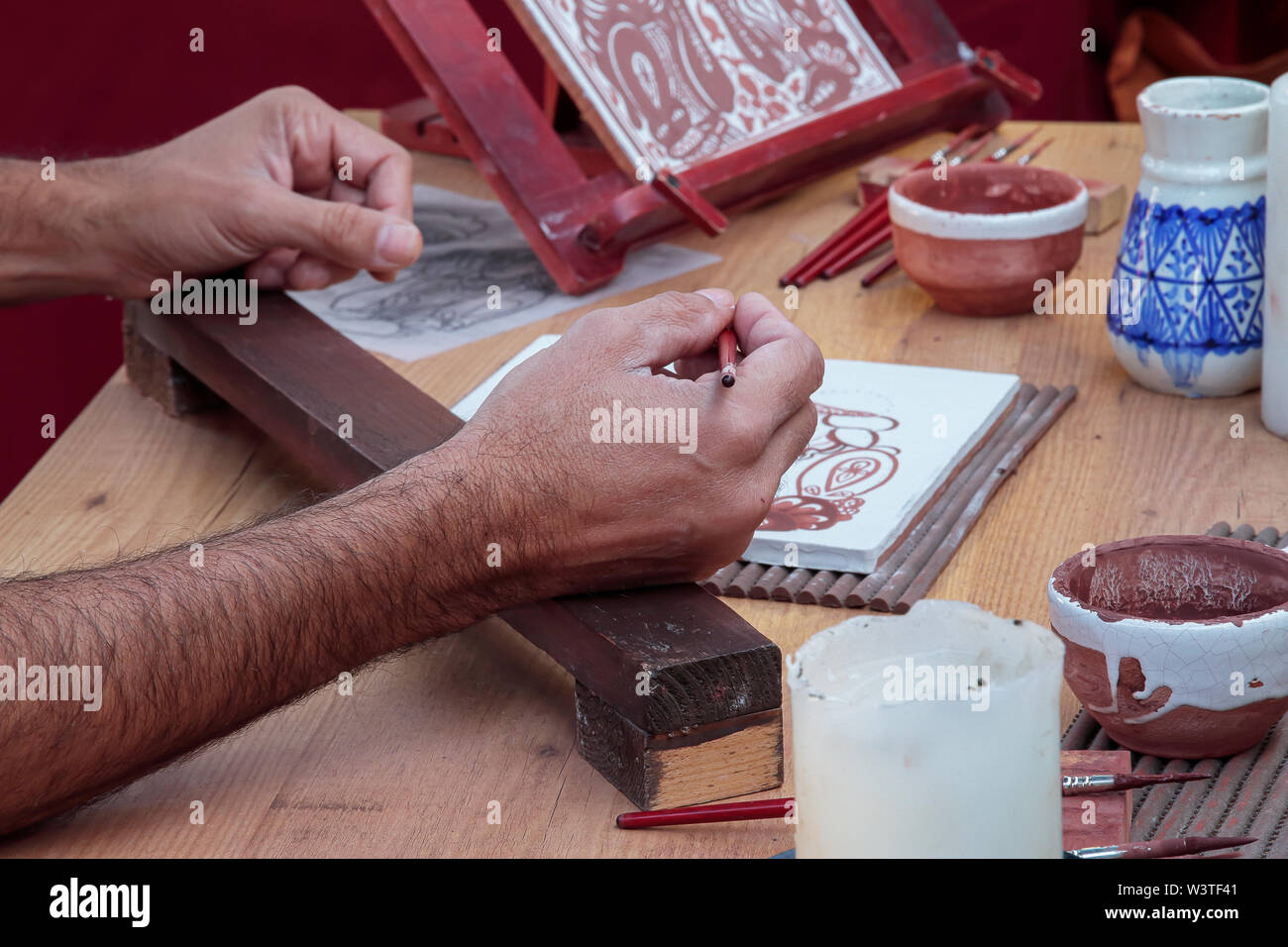foreground of the hands of a craftsman using paintbrushes and tint to ...