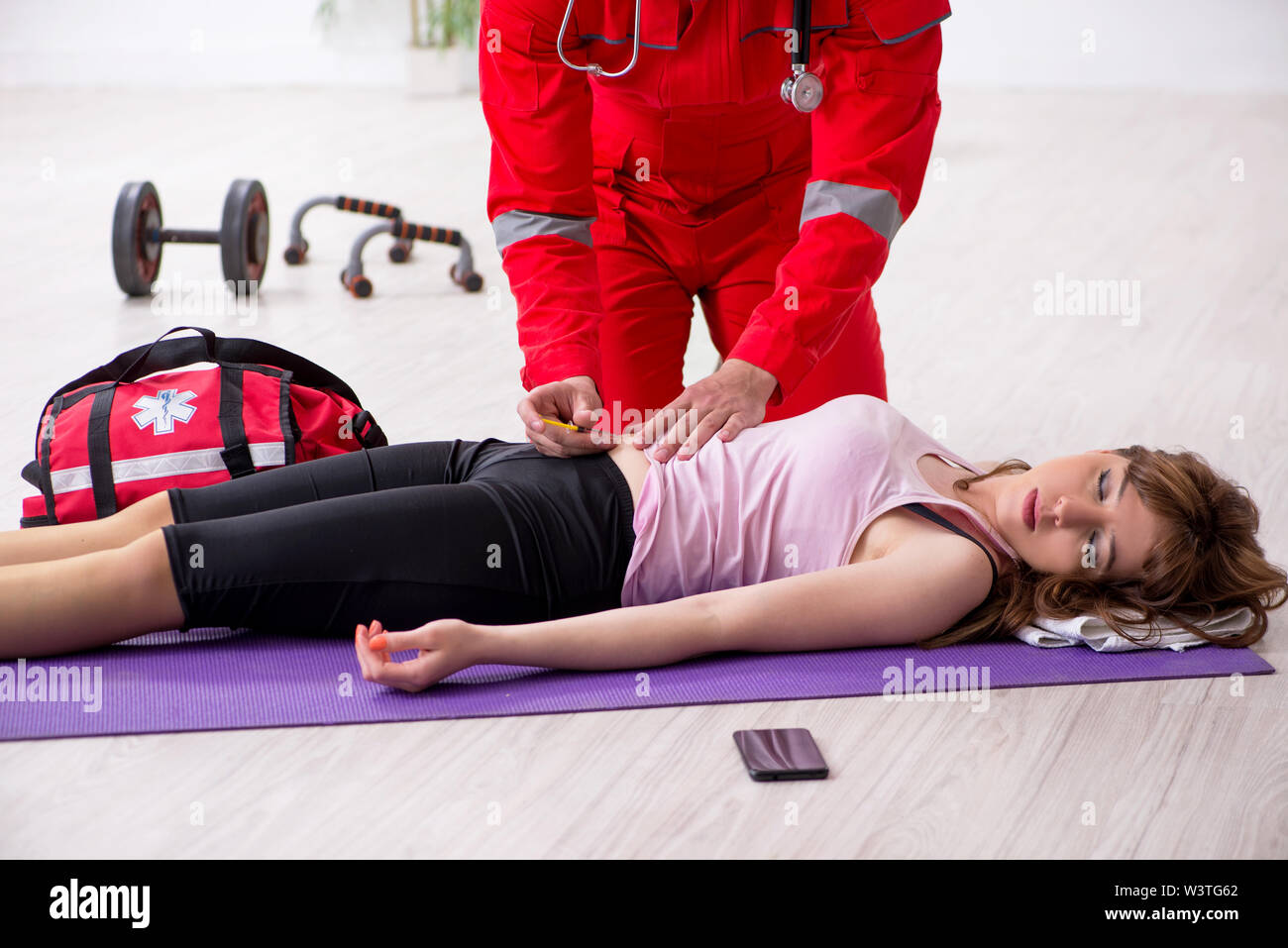The paramedic in red visiting young woman in gym Stock Photo - Alamy