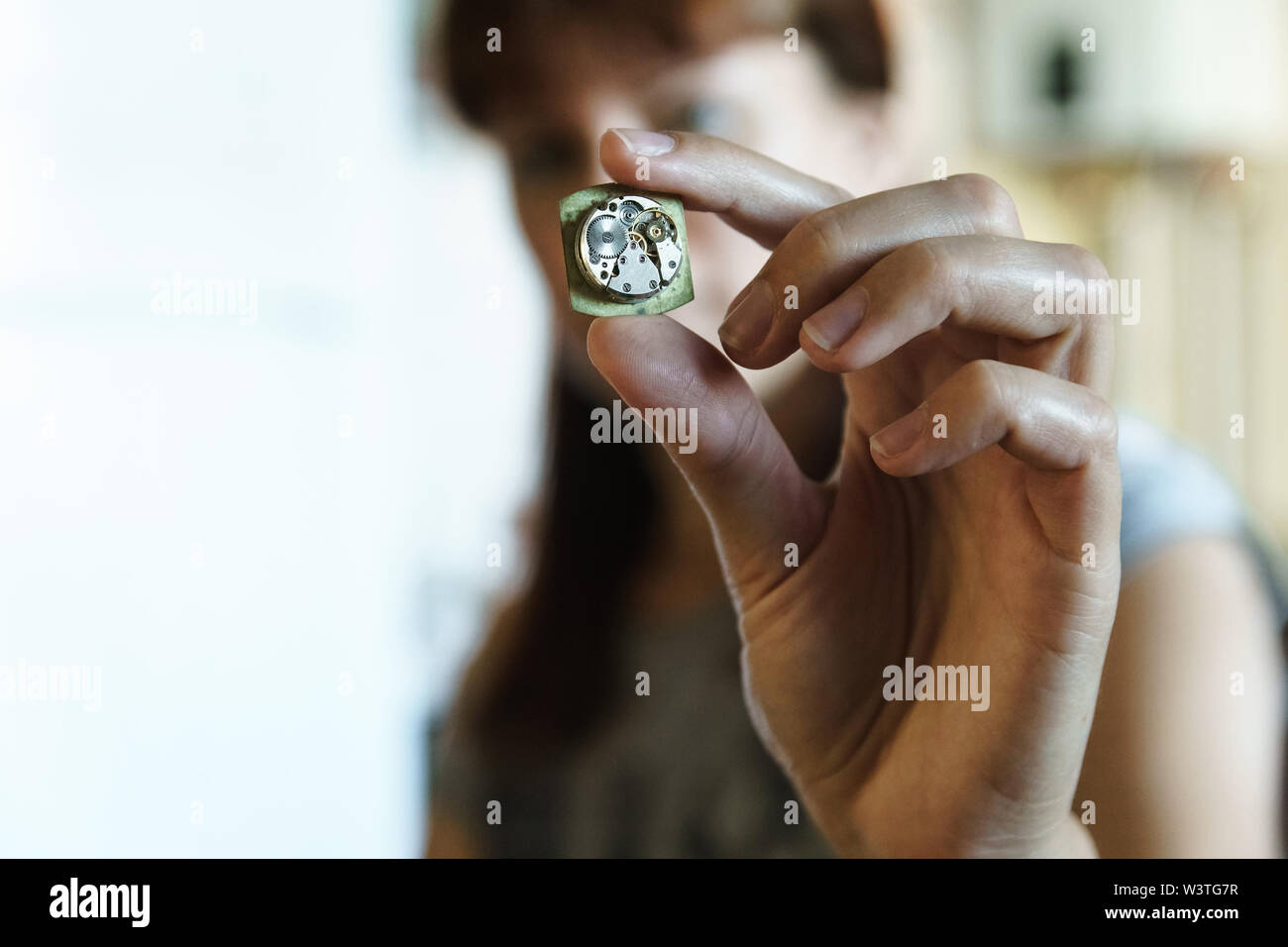 Portrait of woman watchmaker. Girl with blurred face holds clock in ...
