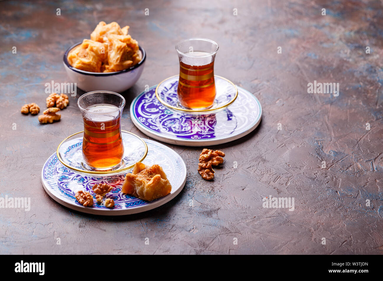 Traditional Turkish black tea in glass at decorative plates on concrete ...