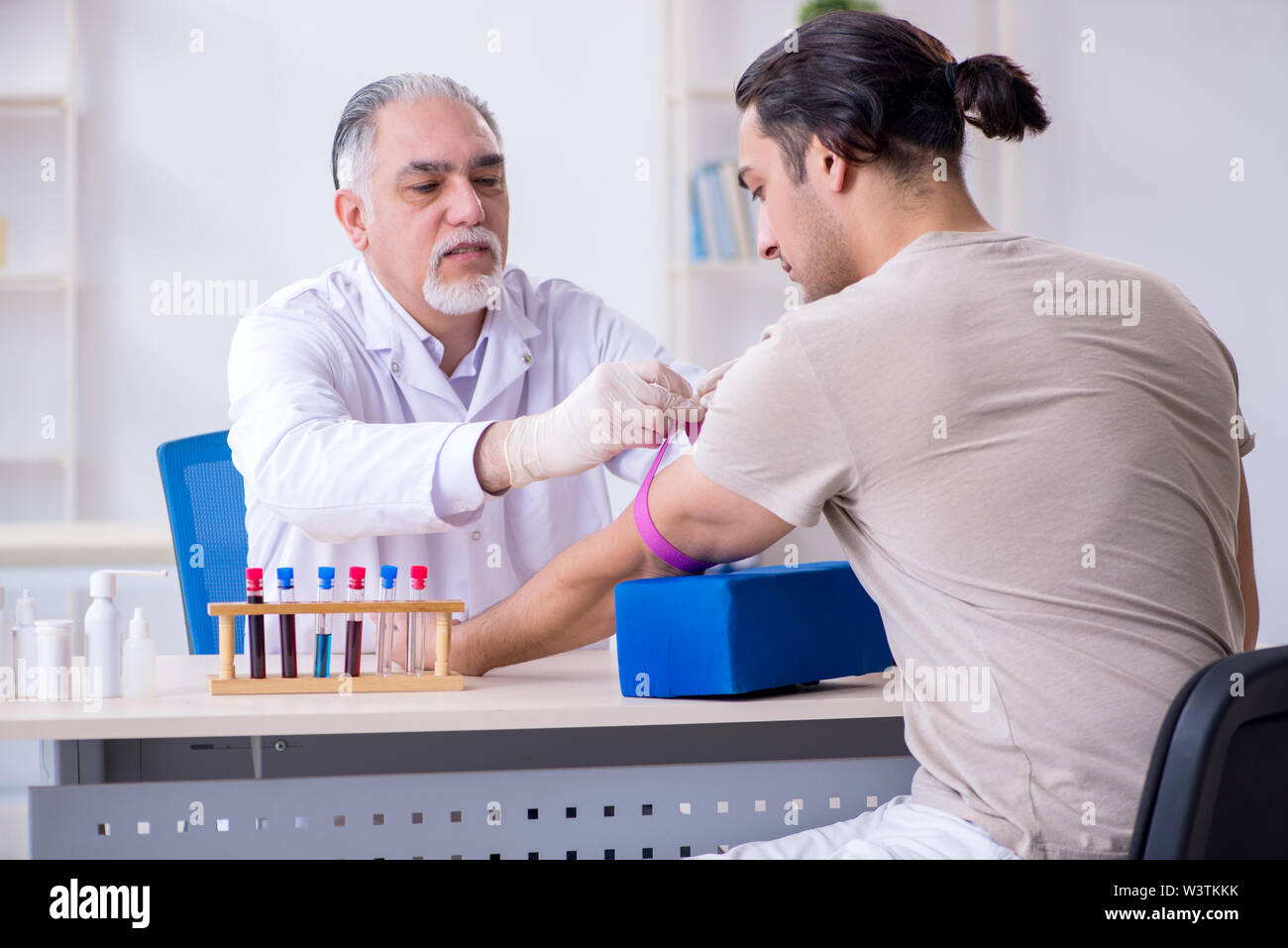 The young handsome man during blood test sampling procedure Stock Photo ...