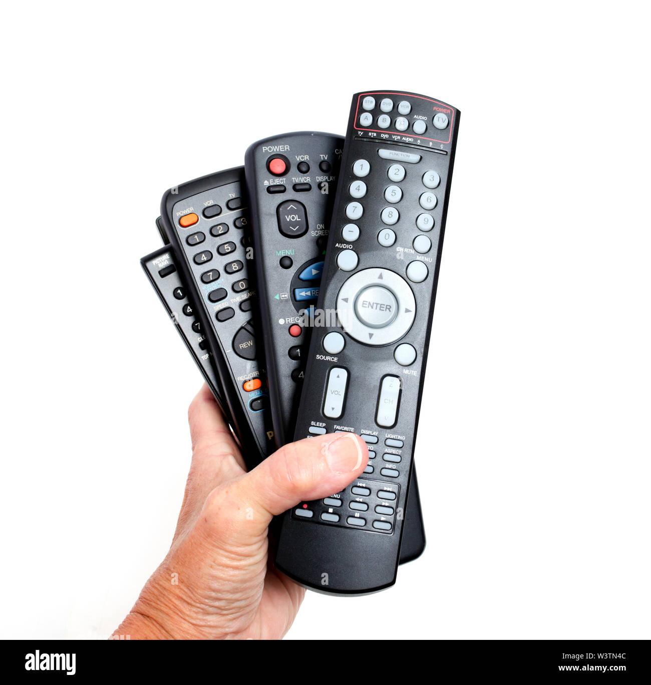 Horizontal close-up shot of a woman’s hand holding four remote controls ...