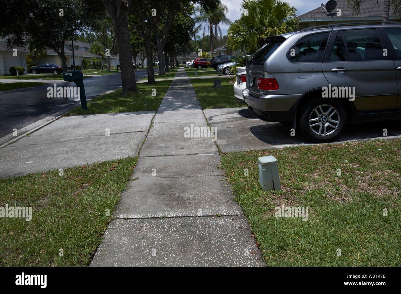 sun shining on concrete footpath sidewalk through gated community in ...