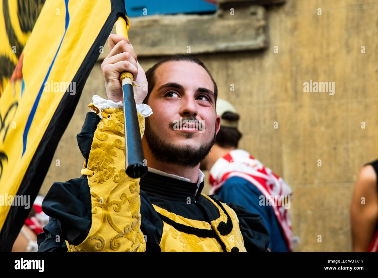 A young man waves a flag representing his contrada, also known as a ...