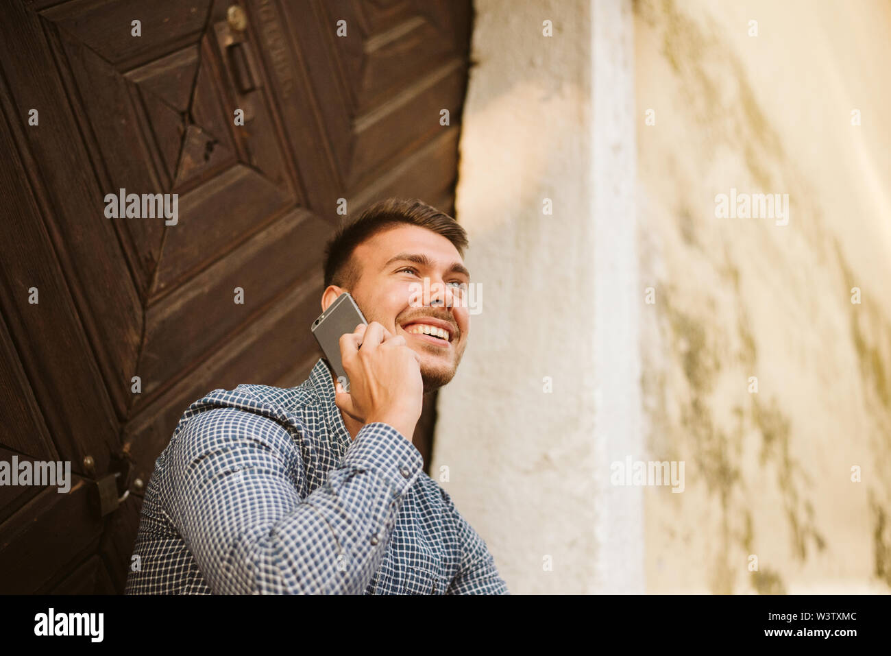 Young man sitting in a cafe, drinking coffee and talking on a mobile ...