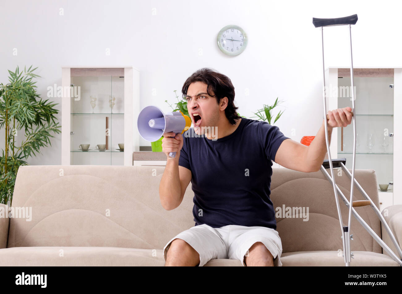 The leg injured young man suffering at home Stock Photo - Alamy