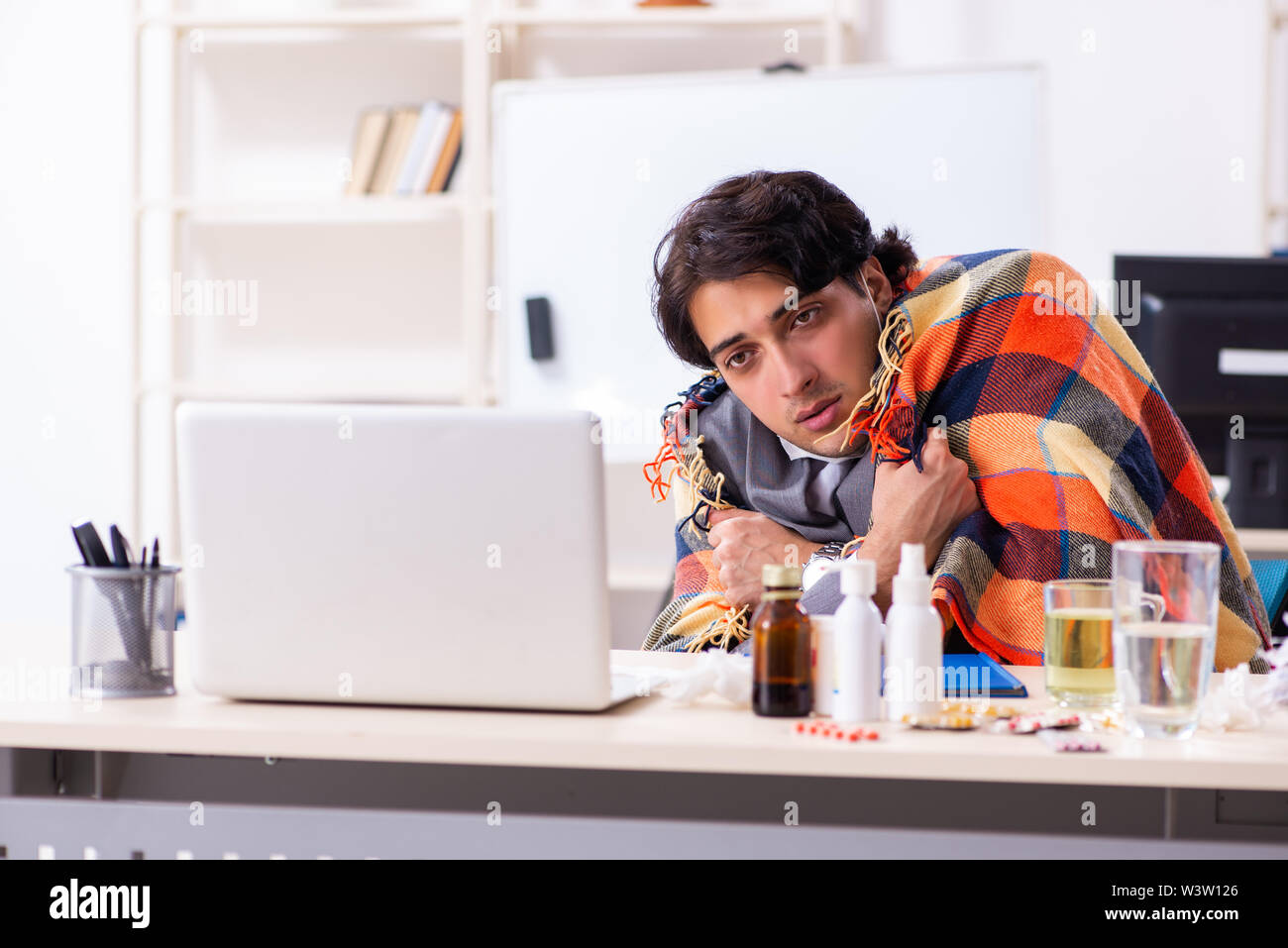 Young male employee suffering at workplace Stock Photo - Alamy