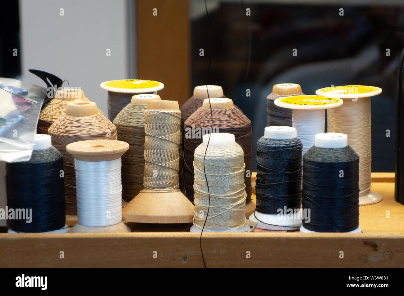 Many spools of thread on the work area of a tailor who performs ...