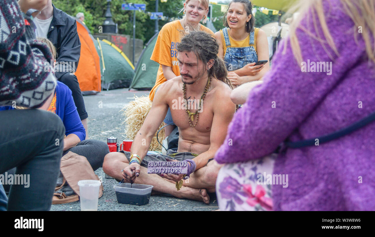 A climate activist seats on the pavement as he paints during the ...