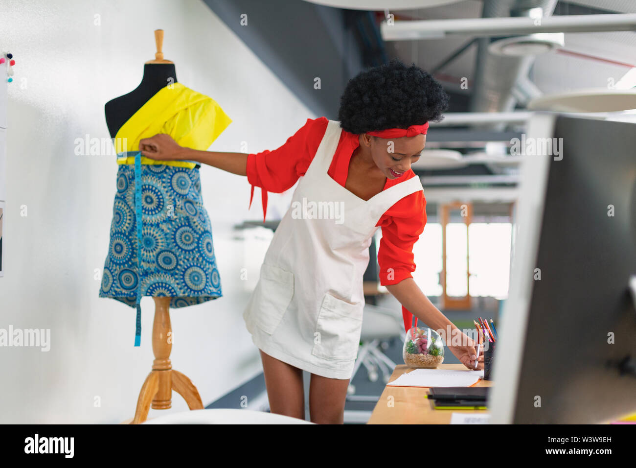 Female fashion designer using measuring table on a mannequin in studio ...
