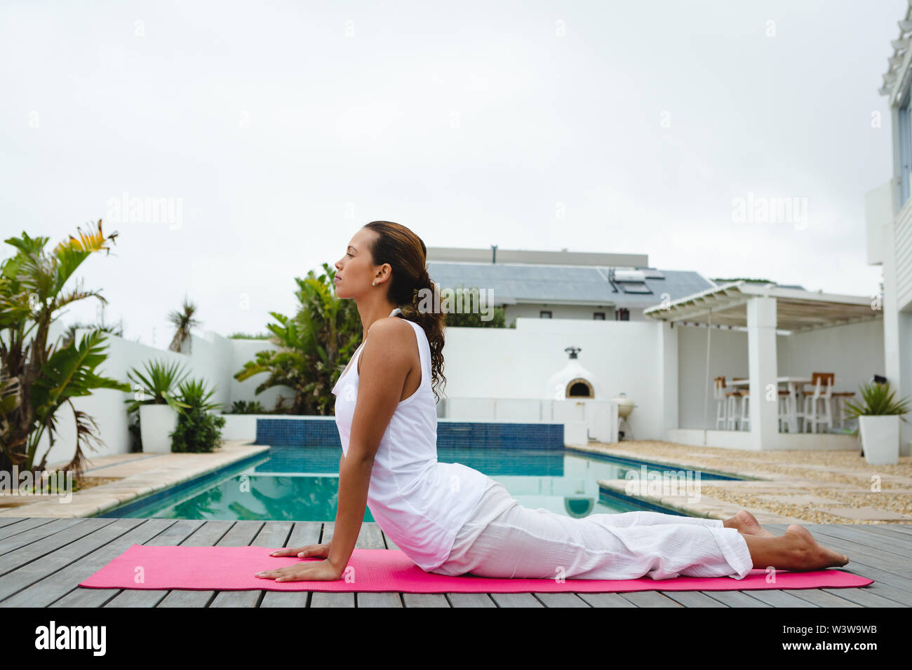 Woman performing yoga near swimming pool in the backyard Stock Photo ...