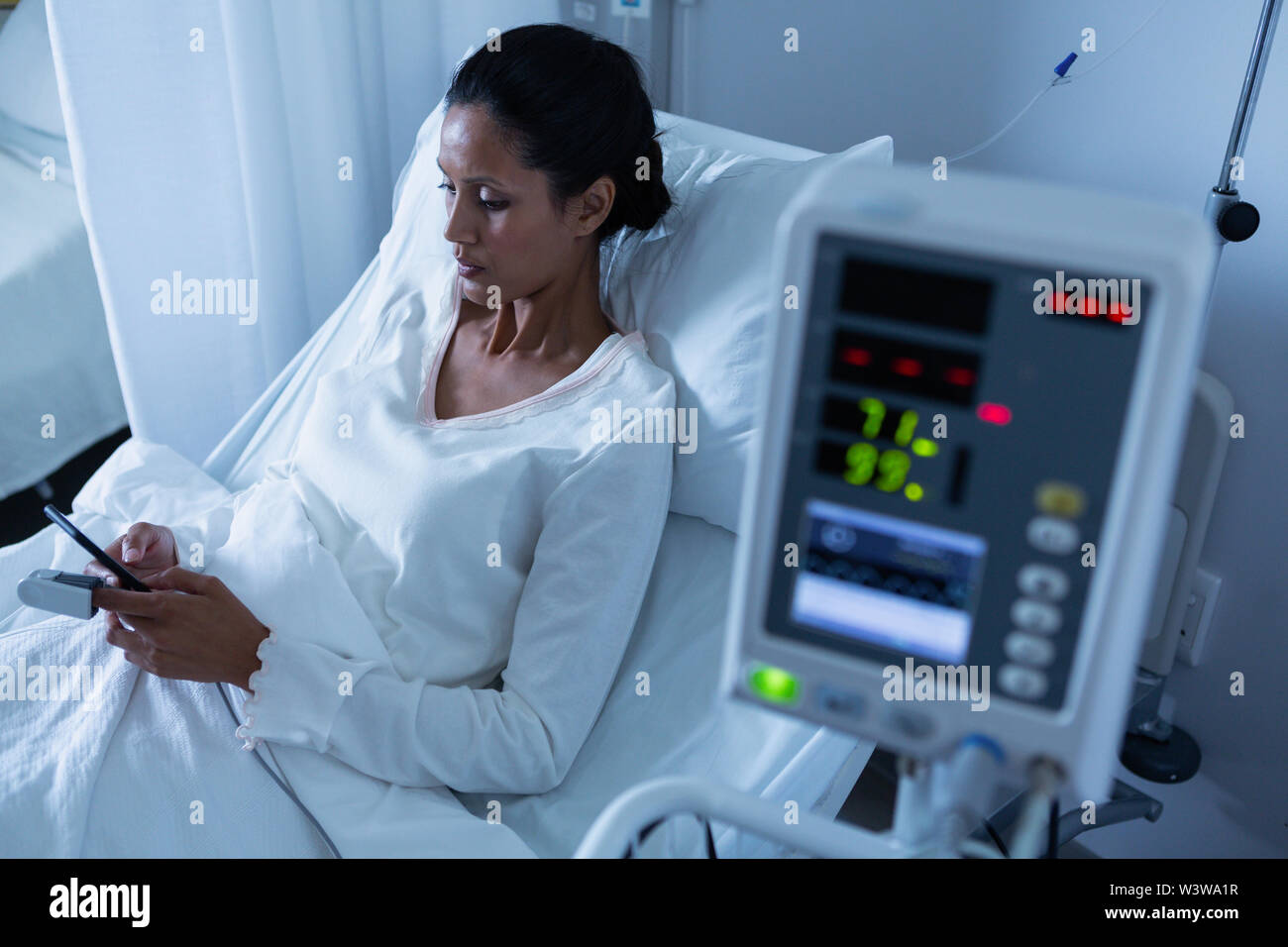 Female patient using mobile phone while relaxing on bed Stock Photo - Alamy