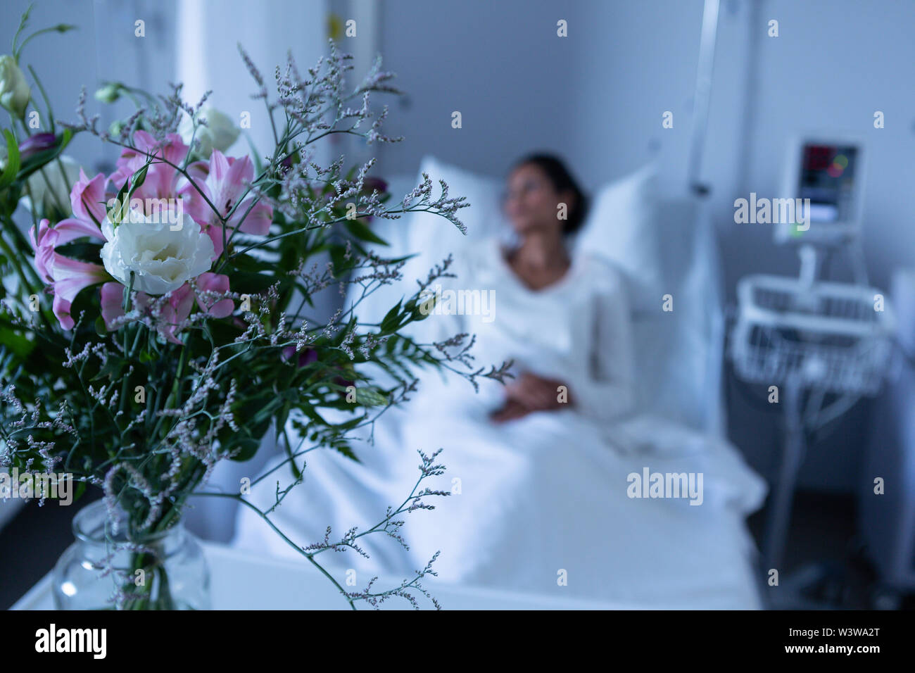 Flower in a vase on table in front of hospital bed Stock Photo - Alamy