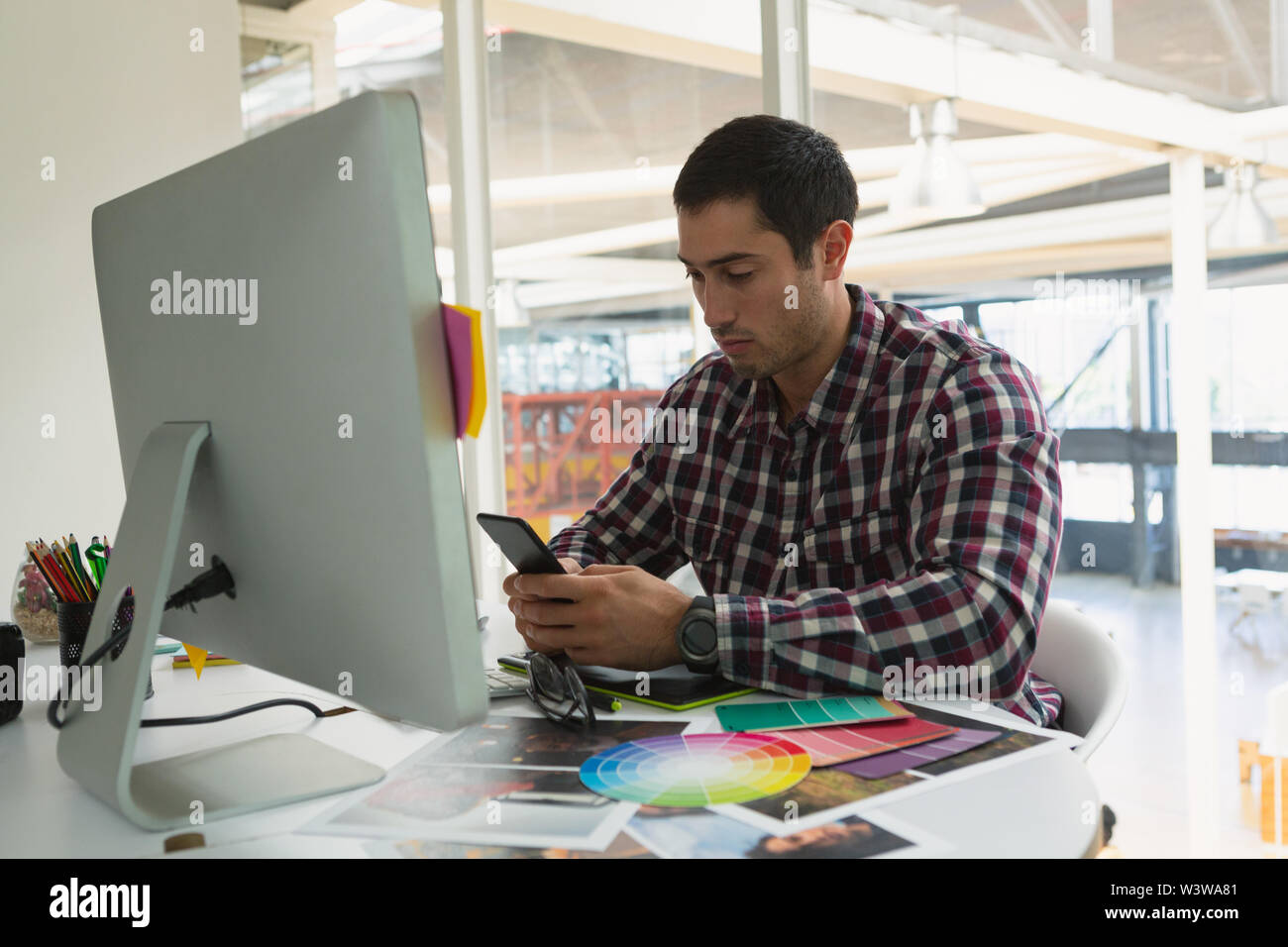 Male Graphic designer using mobile phone at desk Stock Photo - Alamy