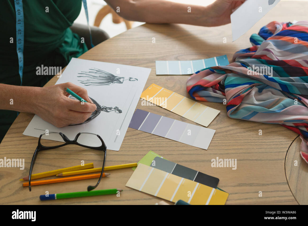 Female fashion designer drawing sketch on a table Stock Photo - Alamy