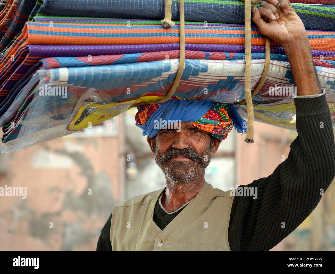 Indian Rajasthani salesman carries on his head a stack of colourful ...