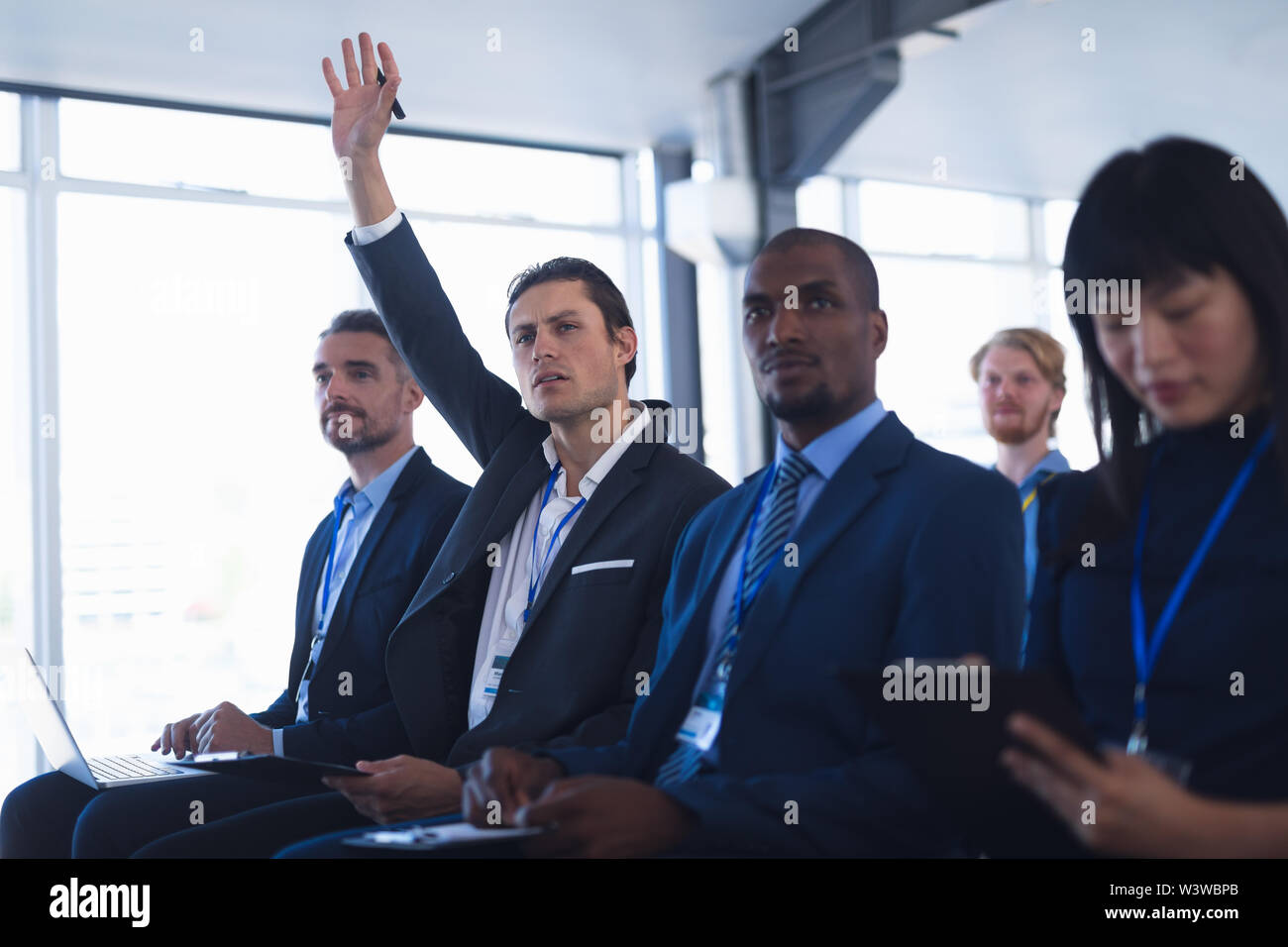 Businessman raising his hand while attending business seminar Stock ...
