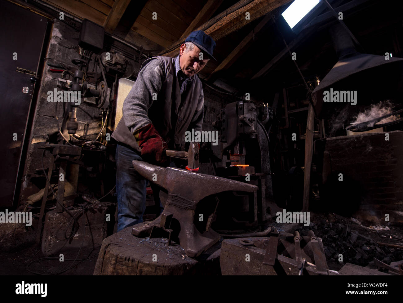 blacksmith manually forging the red hot molten metal on the anvil in ...