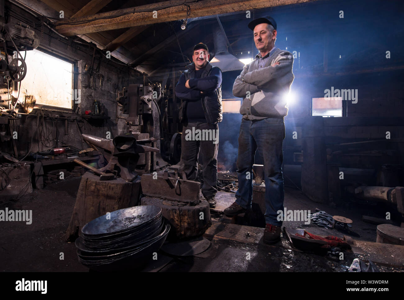 portrait of two generations confident blacksmith standing with crossed ...