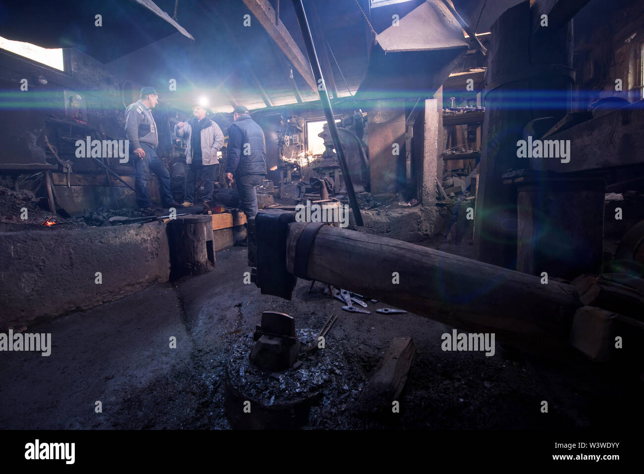 old mechanical hammer in blacksmith traditional workshop with workers ...