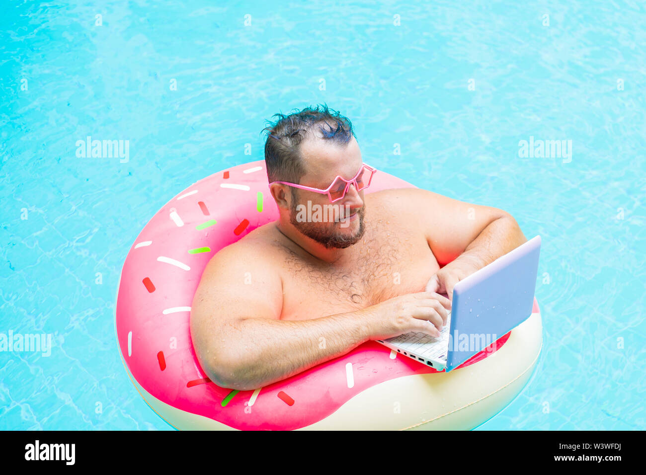 serious Fat funny man in pink inflatable circle in pink glasses works ...