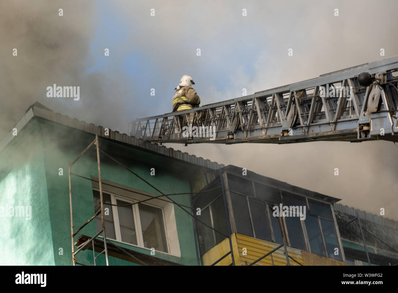 Firefighters on the stairs extinguish a fire on the roof of a ...