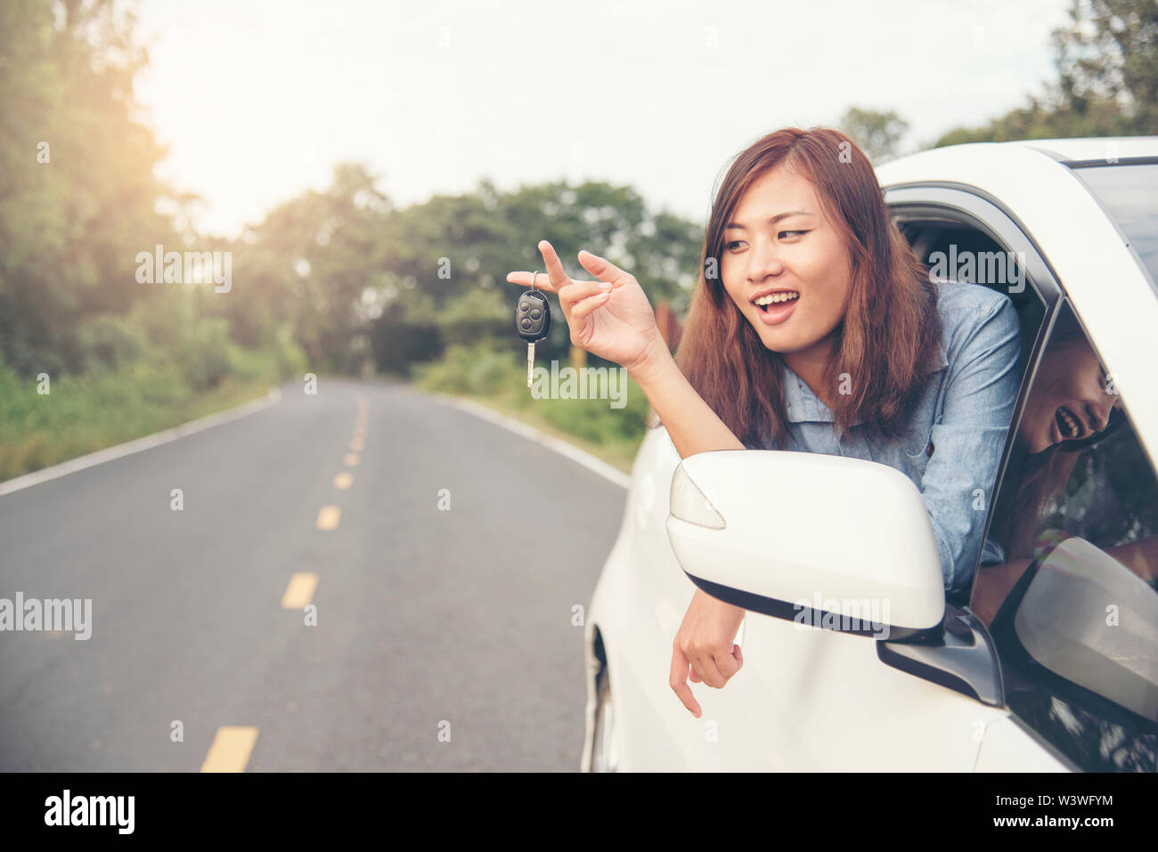 beautiful woman got new car. showing car key from window out of new car ...