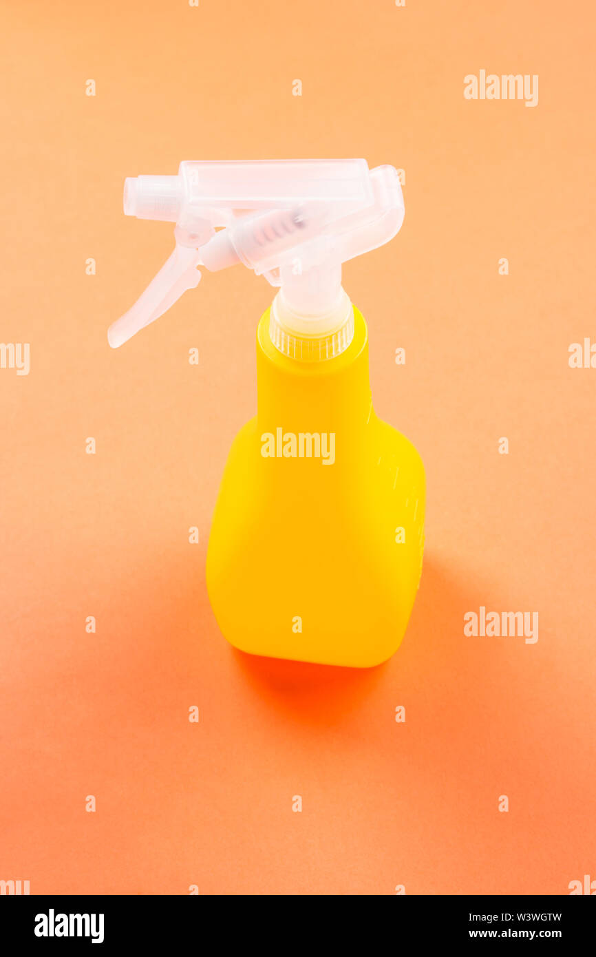 Yellow spray bottle for cleaning or water on orange background. Minimal ...