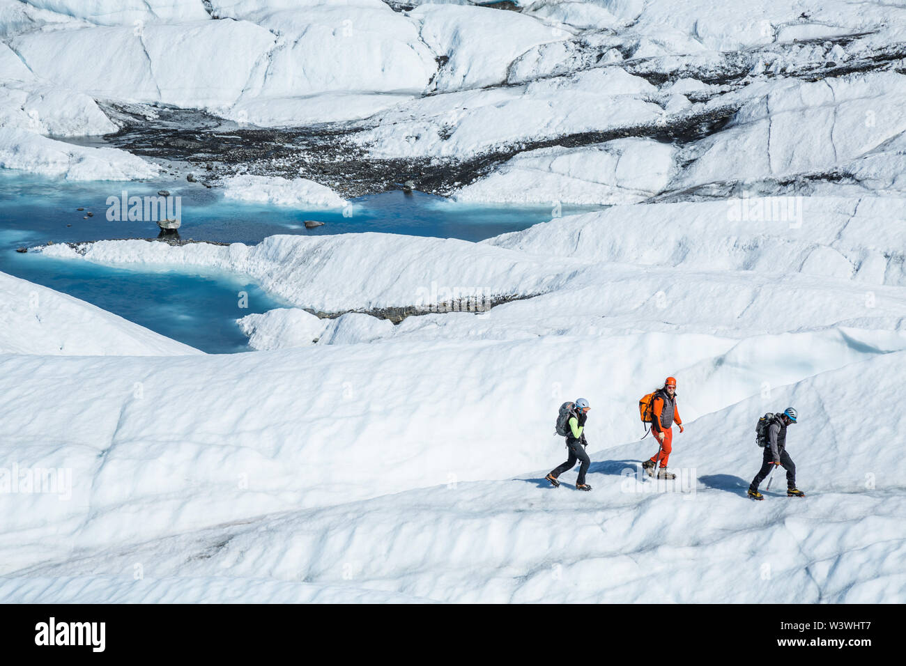 Three ice climbing and glacier trekking guides hiking across the white ...