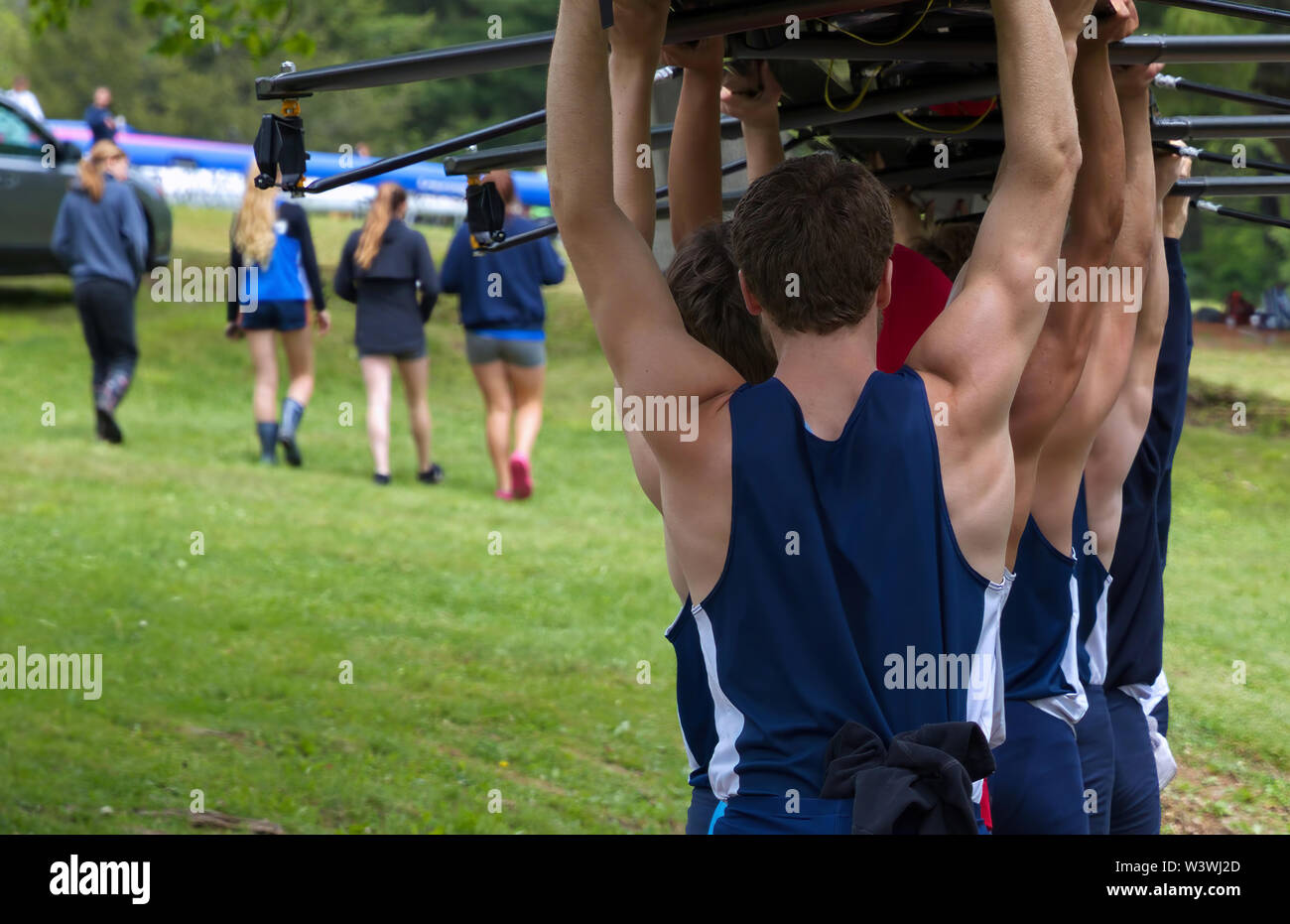 Muscular rowing athletes or a crew carrying back their boat after a ...