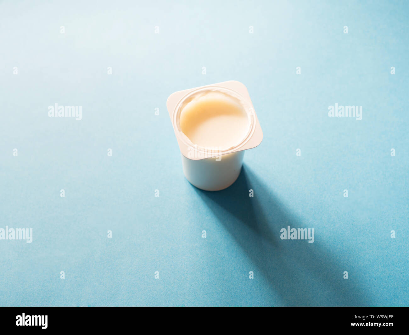 Plain yogurt in plastic glass on monochrome blue background Stock Photo ...
