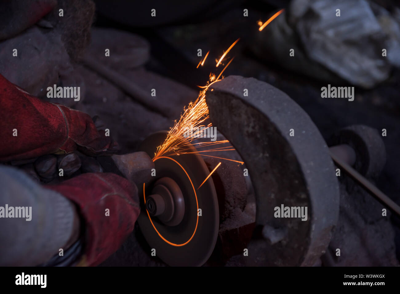 the blacksmith polishing metal products making sparks while using a ...