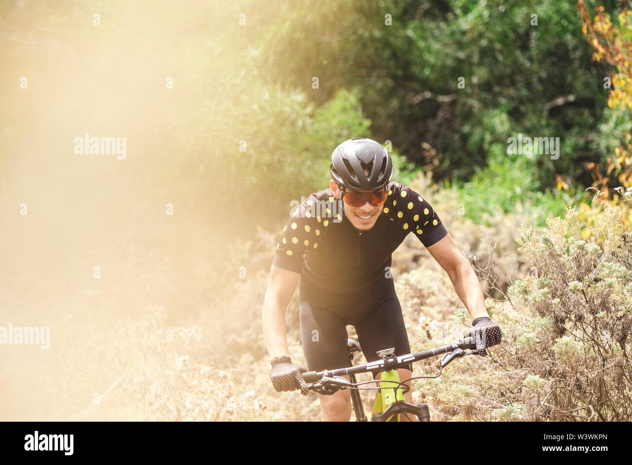 Upper body action photo of smiley male mountain bike cyclist in forest ...