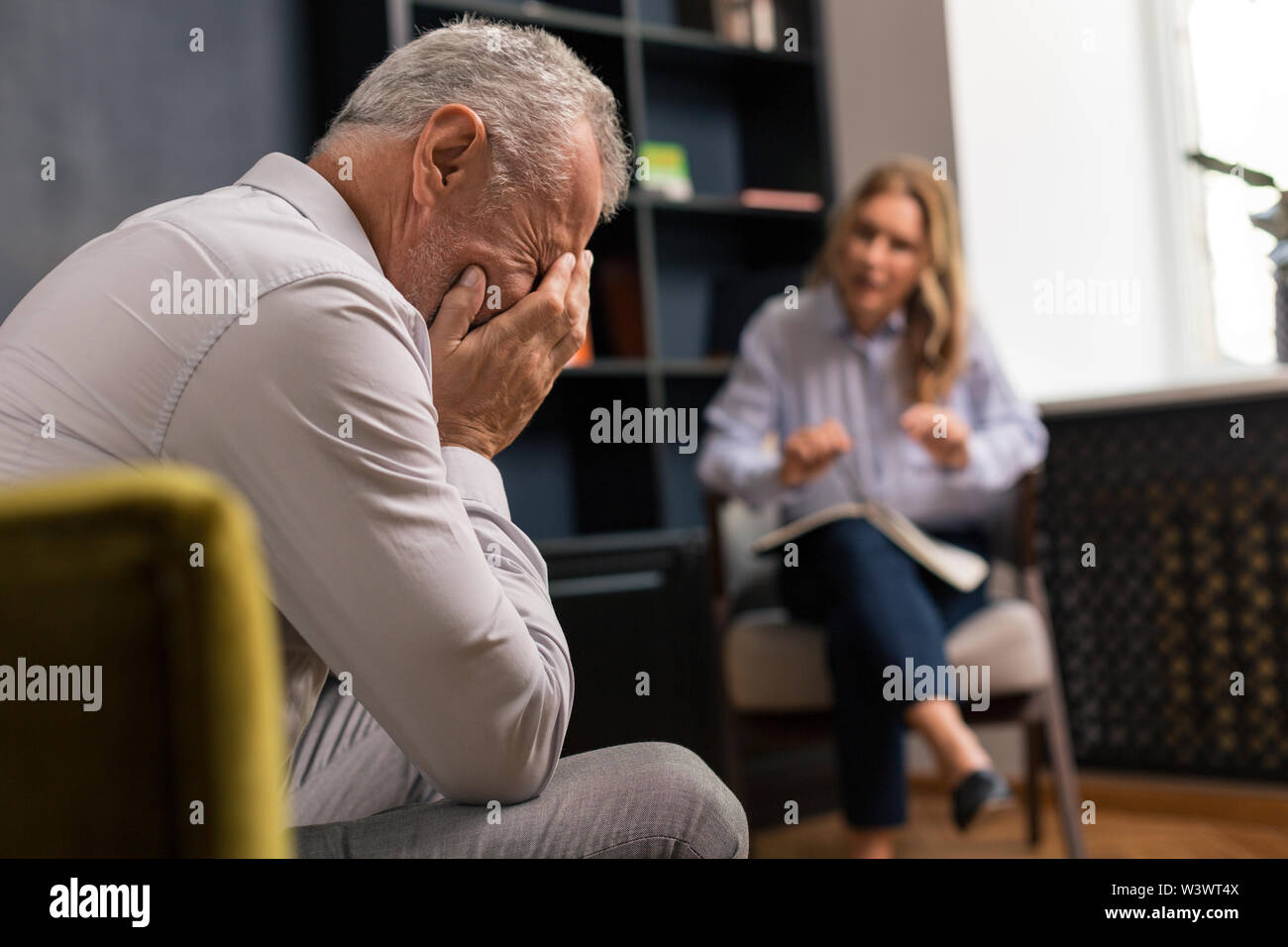Depressed grey-haired man covering his face with hands Stock Photo - Alamy