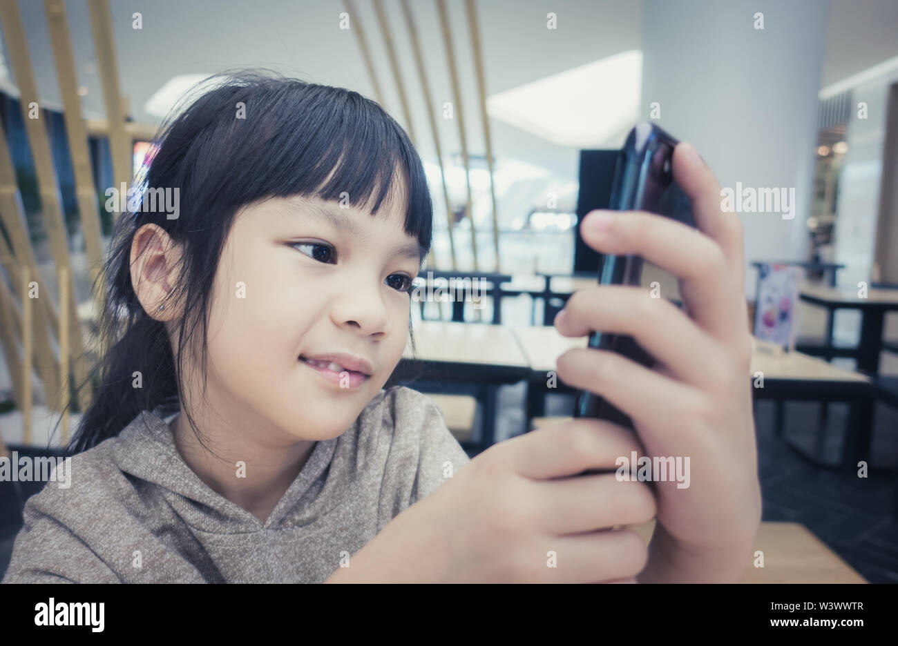 Asian kid is talking on speaker phone in cafe Stock Photo - Alamy