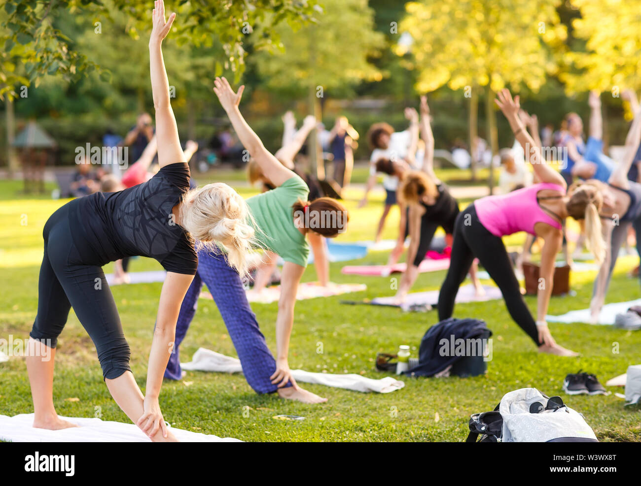 big group of adults attending a yoga class outside in park Stock Photo ...