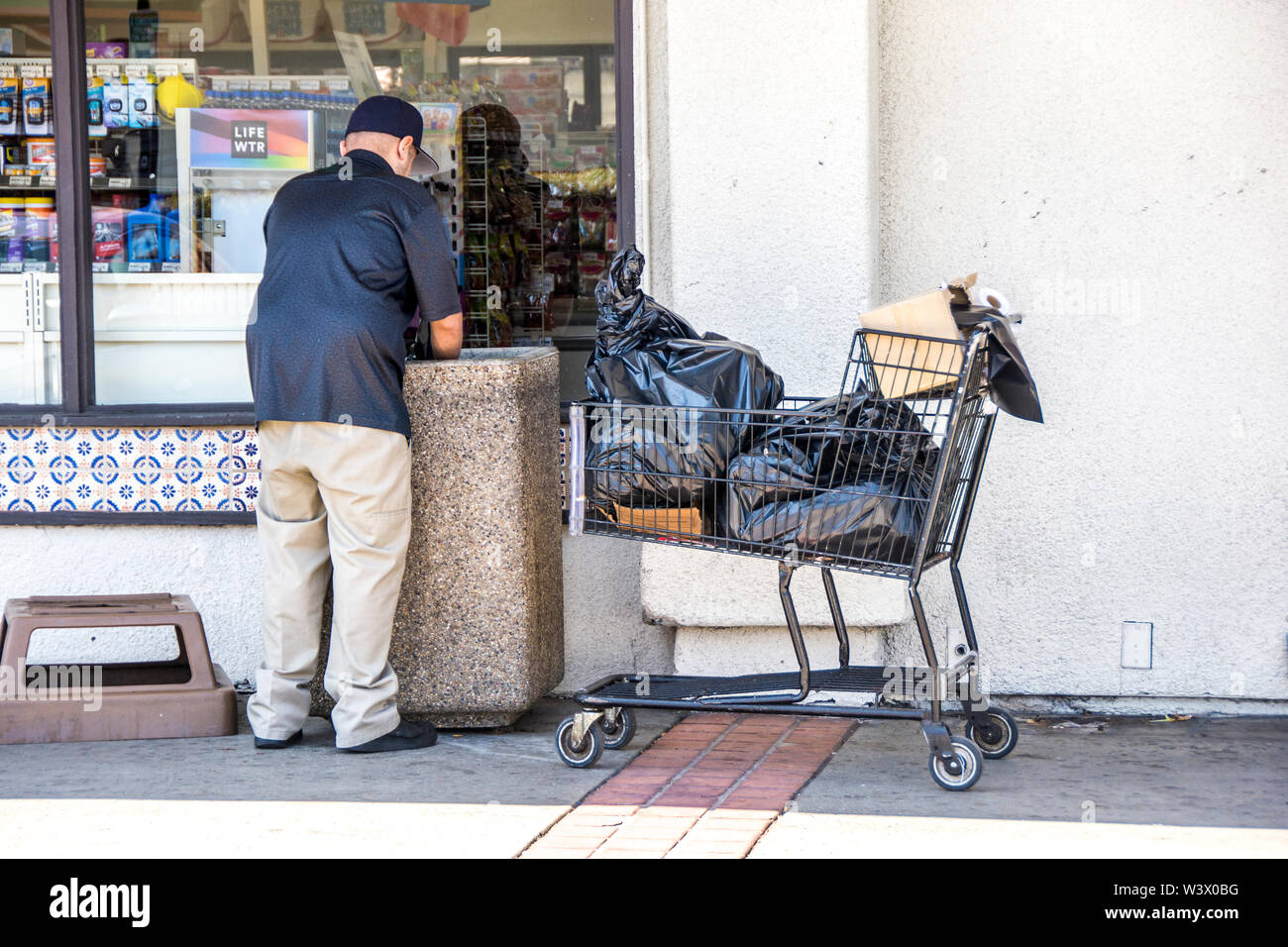 A homeless man outside a 7 -11 Convenience Store looking for things to ...