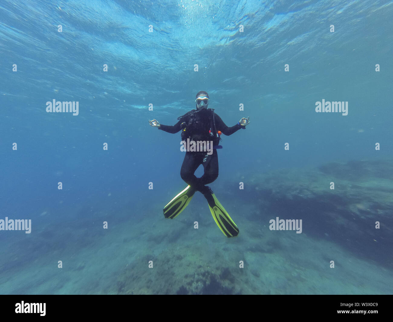 Young female scuba diver in the lotus yoga position during a dive in ...