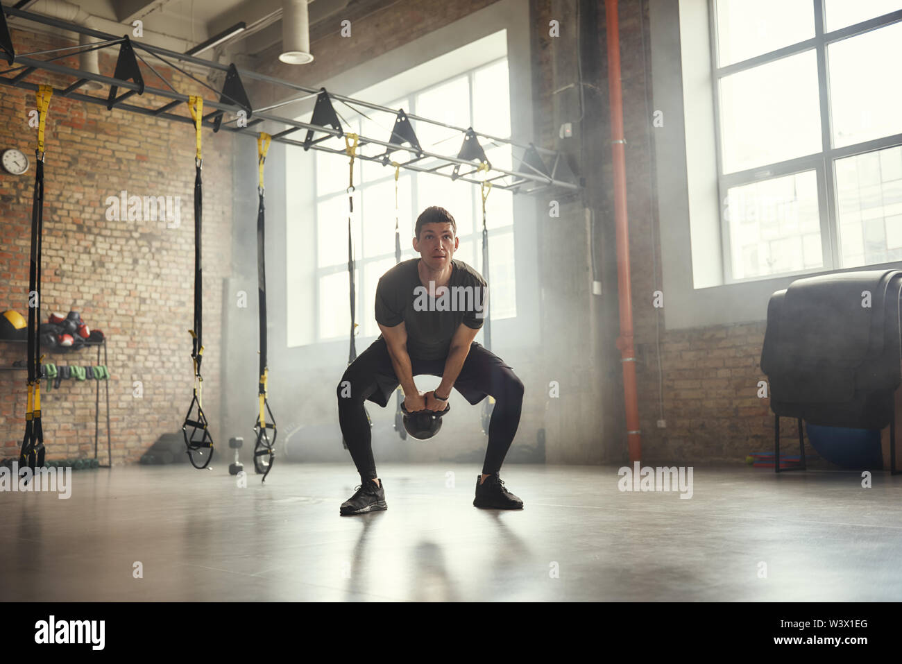 Weight exercise. Handsome and strong young man in sports clothing ...
