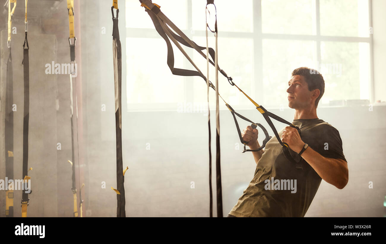 I want to have perfect body. Strong athletic man training his arms with ...