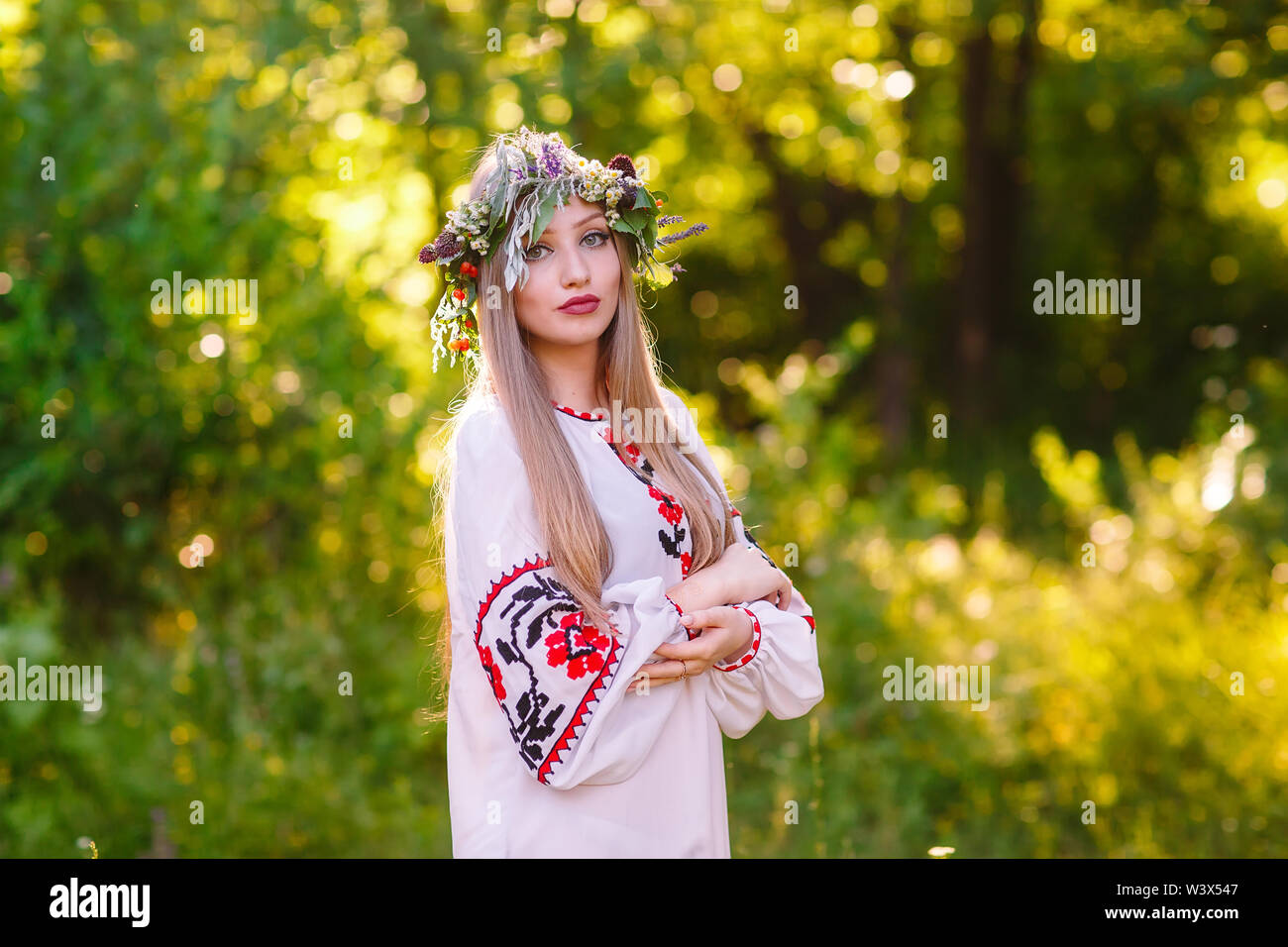 A young girl of Slavic appearance with a wreath of wild flowers on the ...