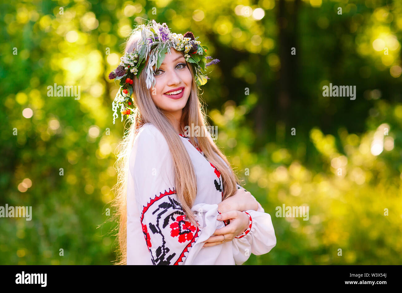 A young girl of Slavic appearance with a wreath of wild flowers on the ...