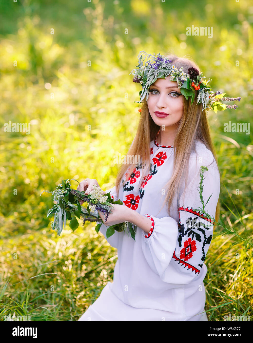A young girl of Slavic appearance with a wreath of wild flowers on the ...