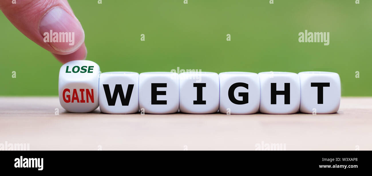 Hand turns a dice and changes the expression "gain weight" to "lose ...